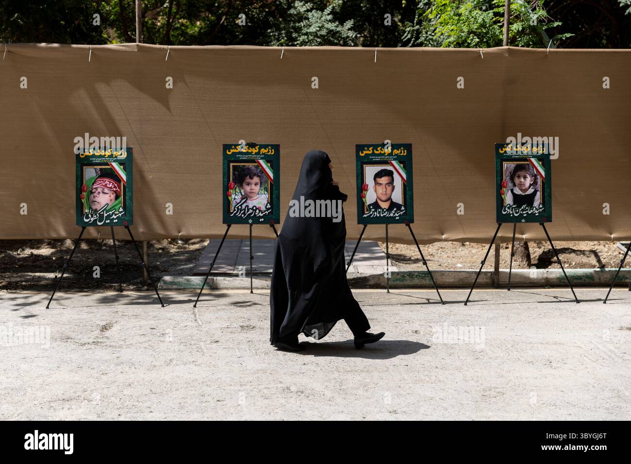 7/19/2025 An Iranian woman walks past portraits of Iranian children who ...