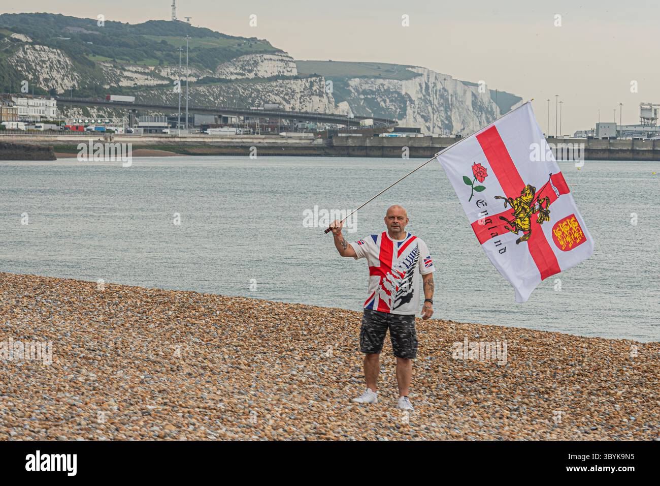 An English 'Patriot' holds aloft the St. George's flag on the beach of ...