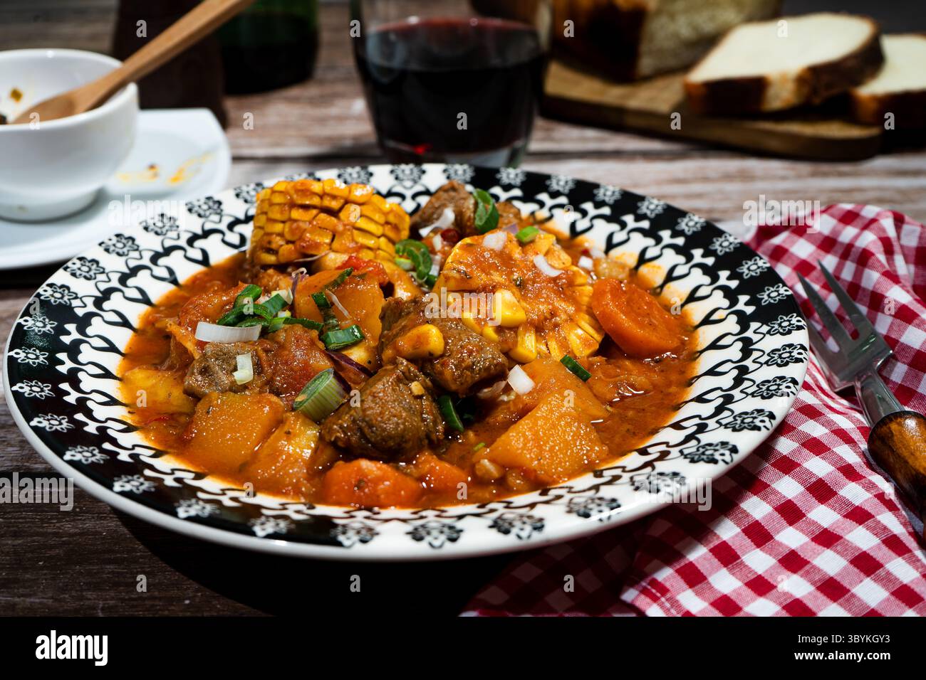 Savory beef stew served with corn on the cob and various vegetables ...