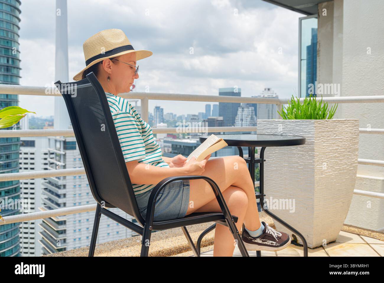 Woman is reading a book at scenic terrace among skyscrapers Stock Photo ...