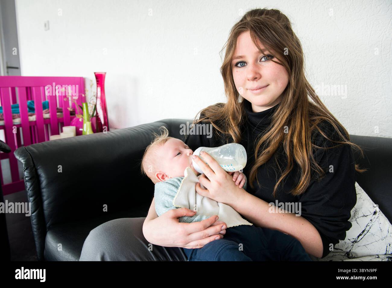 Young mother feeding baby son. Young adult caucasian mother feeding a ...