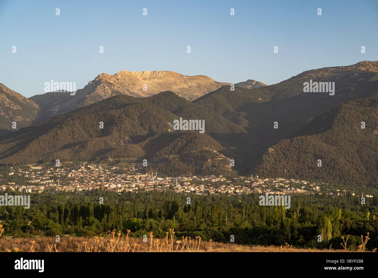 Golden sunlight casts a warm glow over a town surrounded by majestic ...