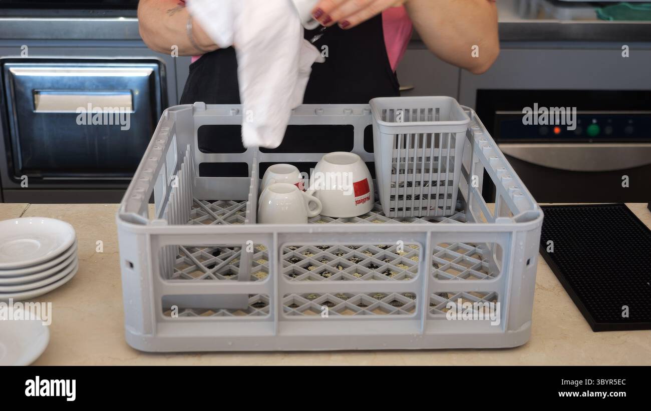 Cremona, Italy - July 19th 2025 A person drying clean cups and saucers ...
