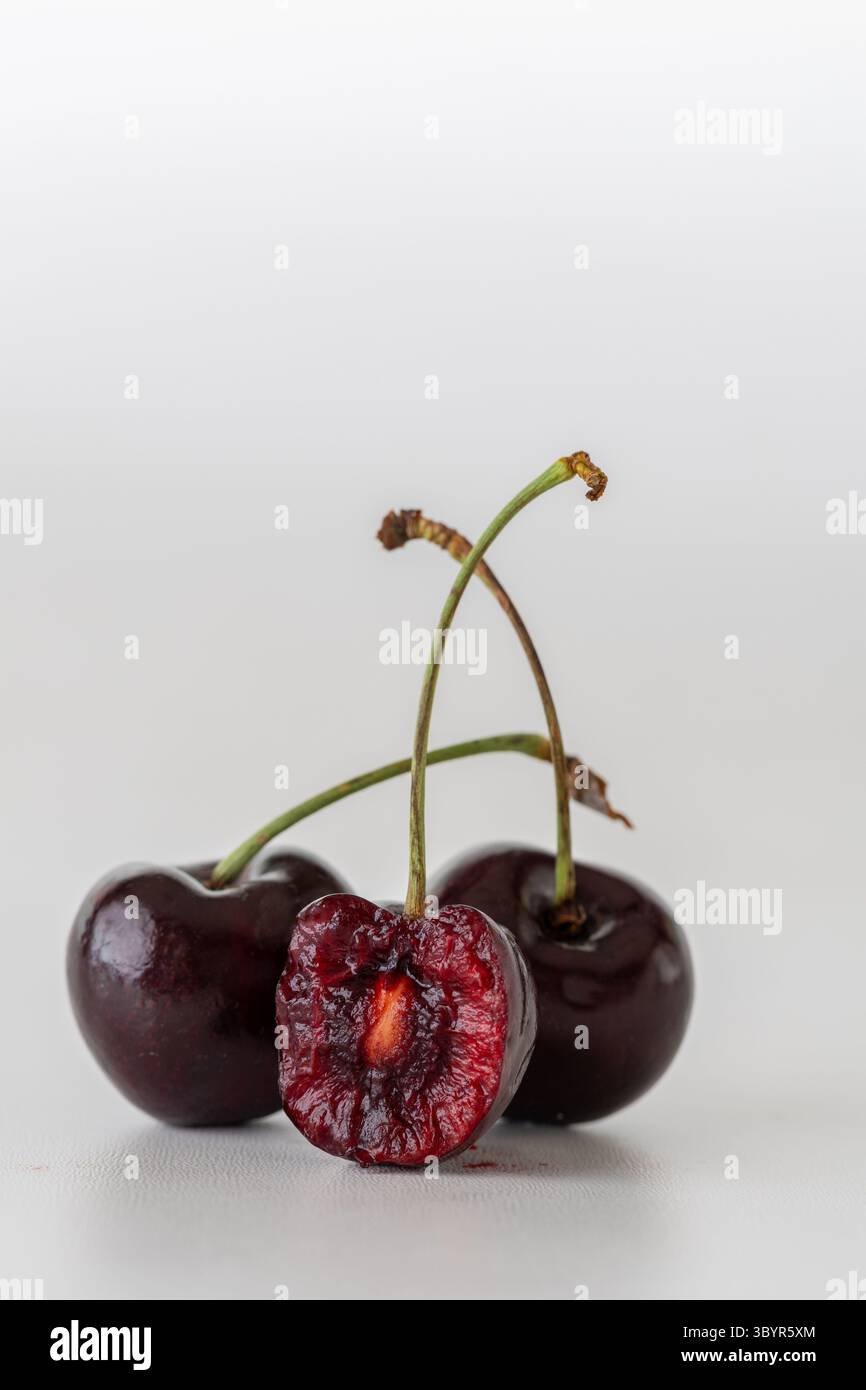 three cherries, one with a bite out out, white background Stock Photo ...