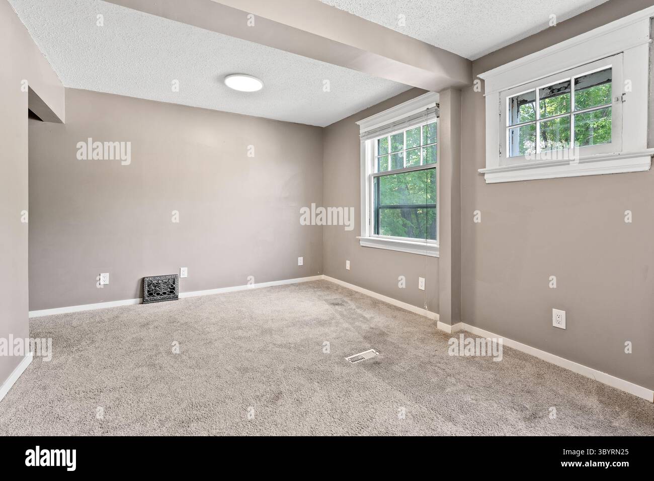 Large, empty room with a tan wall and a white ceiling. The room has a ...