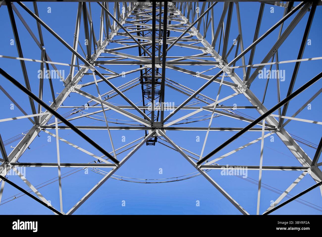 Low-angle view of a towering high-voltage transmission pylon against a ...