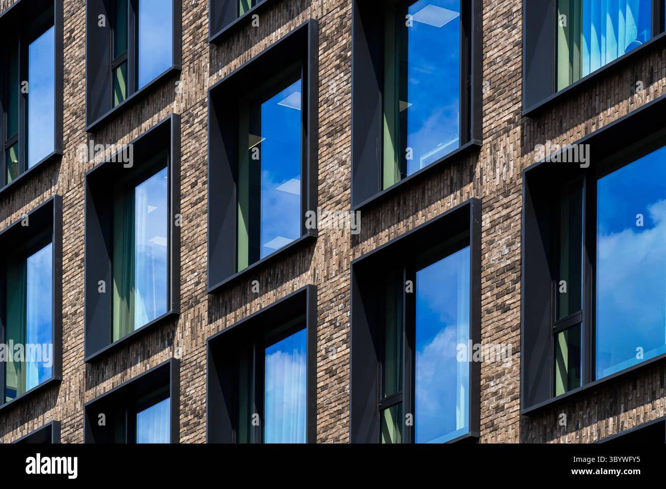 Modern brick residential facade with deep-set reflective windows and ...