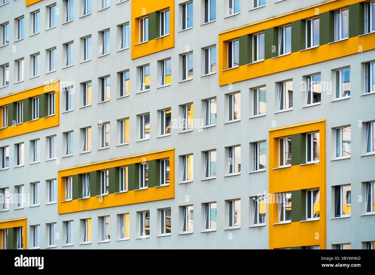 Patterned residential facade with alternating yellow and green window ...