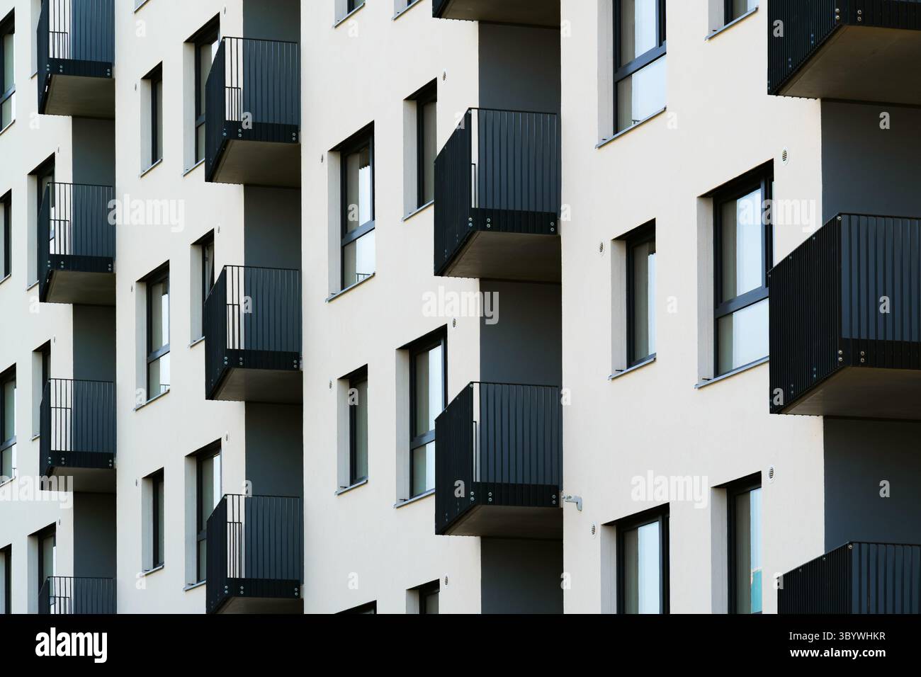 Modern apartment facade with pale walls and recessed black metal ...
