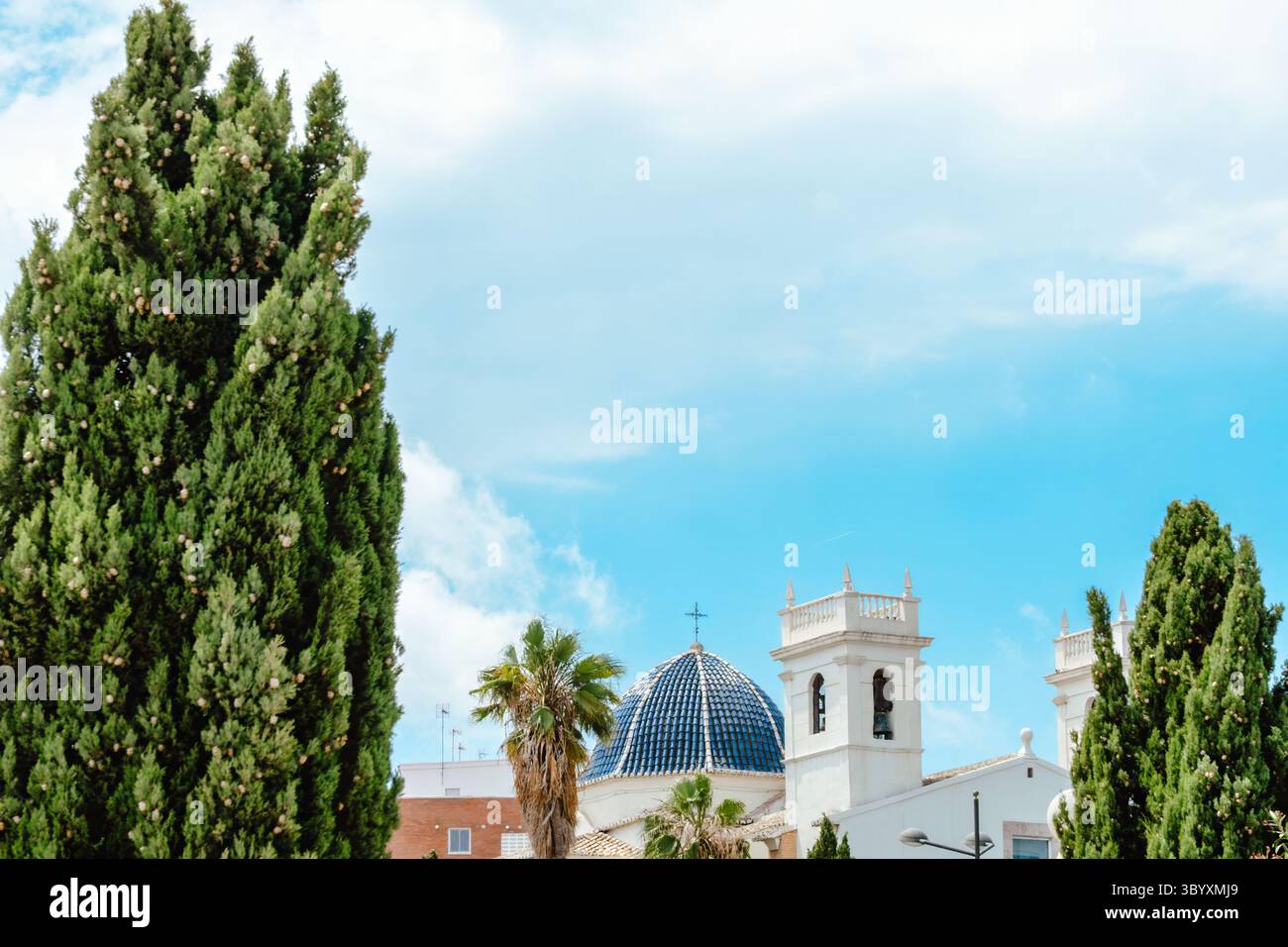 White Catholic church with blue tiled dome and bell towers peeks ...