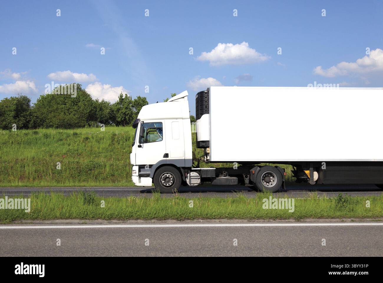 Long lorry with white truck and trailer on highway against blue sky ...
