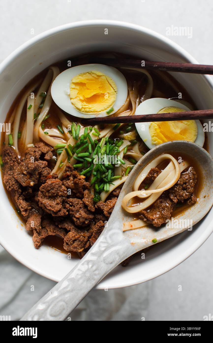 Overhead view of spicy noodle soup in a ceramic spoon, top view of ...
