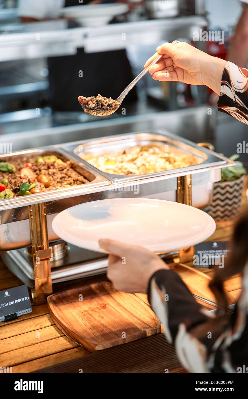 A person serves food from a professional buffet setup with various hot ...