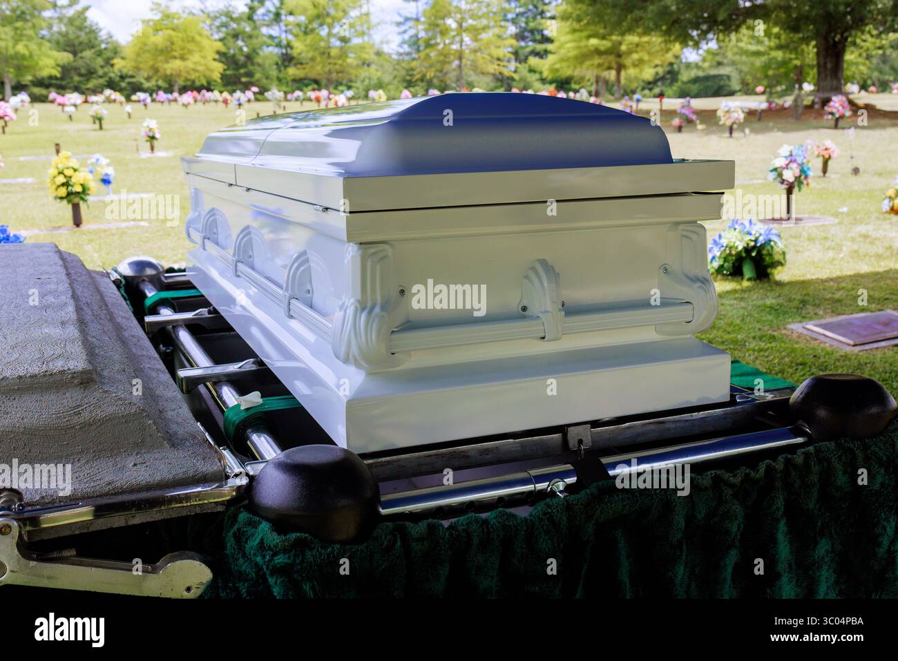 Casket is positioned at gravesite with colorful flowers greenery in ...