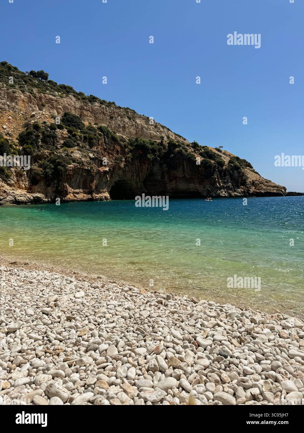 A tranquil beach showcases clear turquoise waters lapping against a ...
