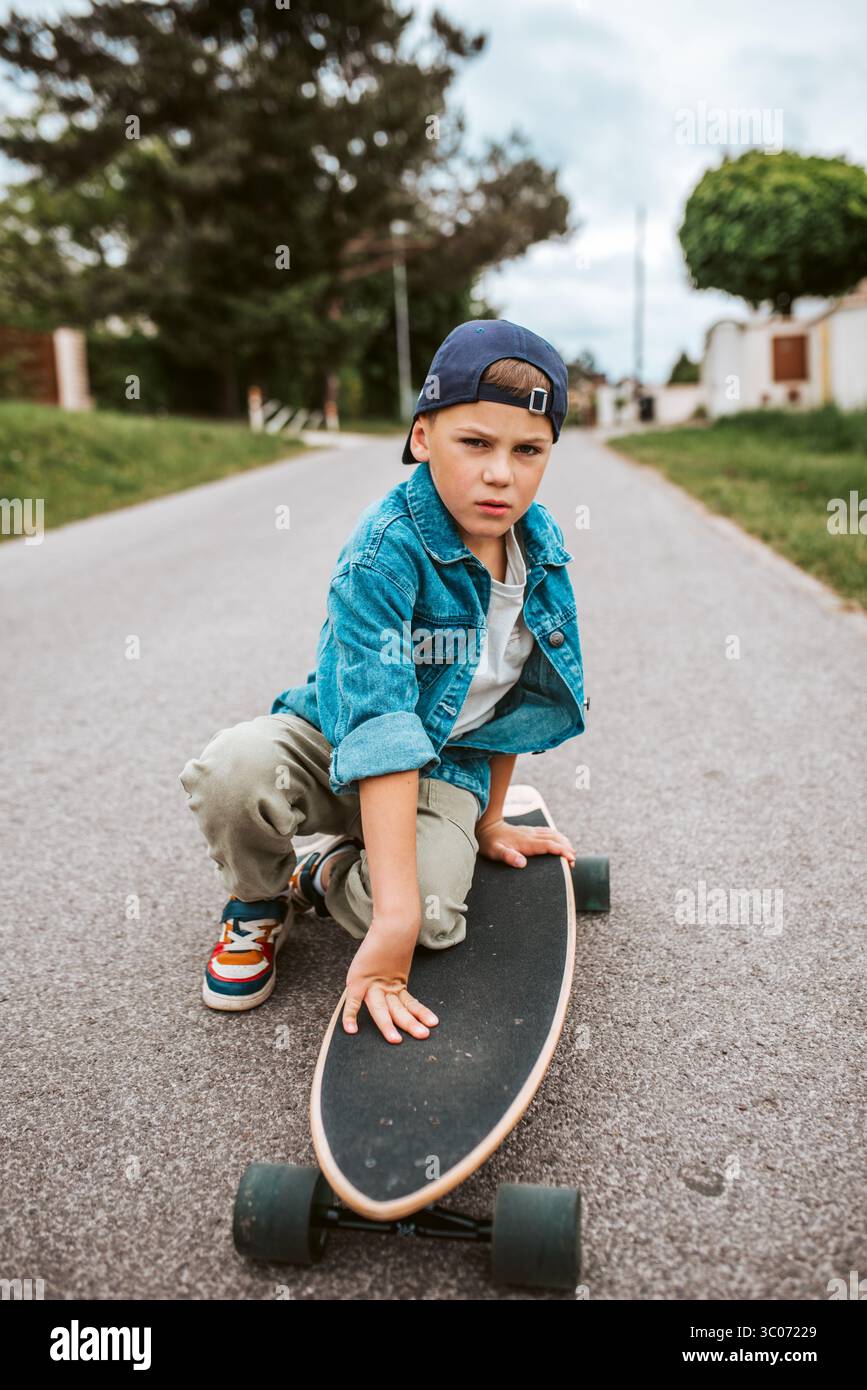 Boy sitting on his longboard on street, enjoying holidays Stock Photo ...