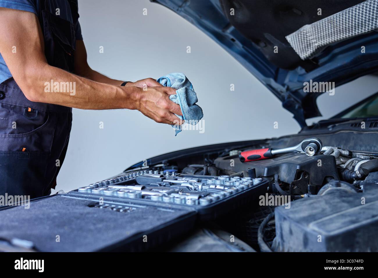 Auto mechanic cleaning dirty hands with cloth after completing car ...