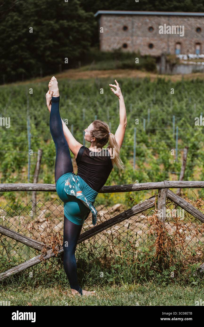 Ballerina practicing an elegant stretch by lifting her leg high in a ...