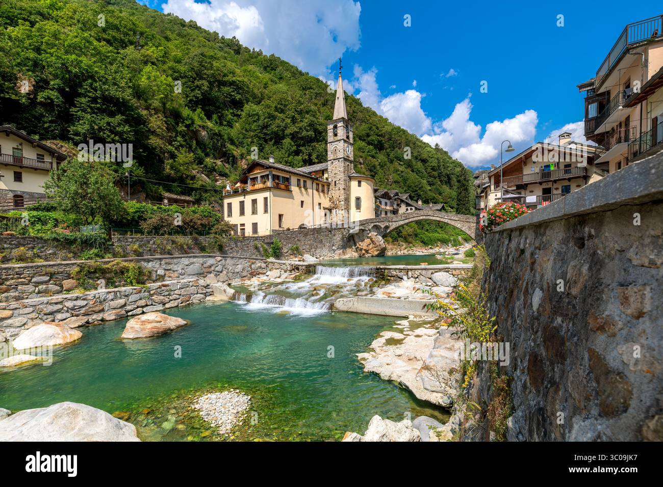 Ancient stone bridge spans the alpine river in a small village of ...