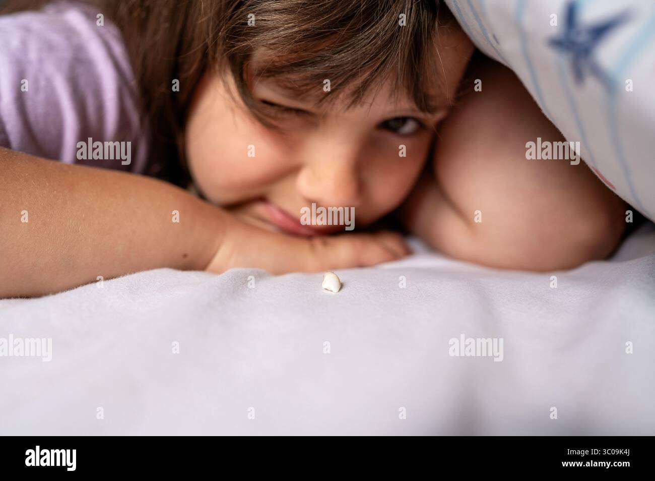 A happy smiling child girl lying with milk tooth under pillow Stock ...