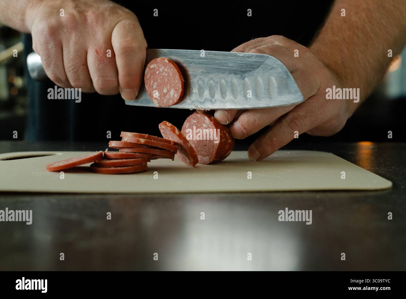 Close-up of hands slicing salami with knife on cutting board Stock ...