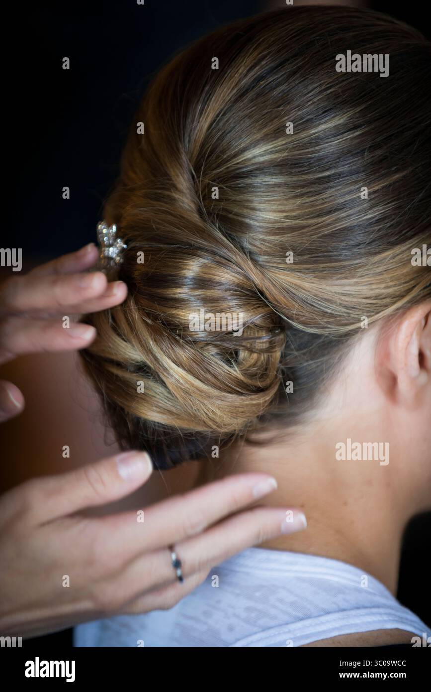 Close-up of hands styling smooth bridal updo with hairpin Stock Photo ...
