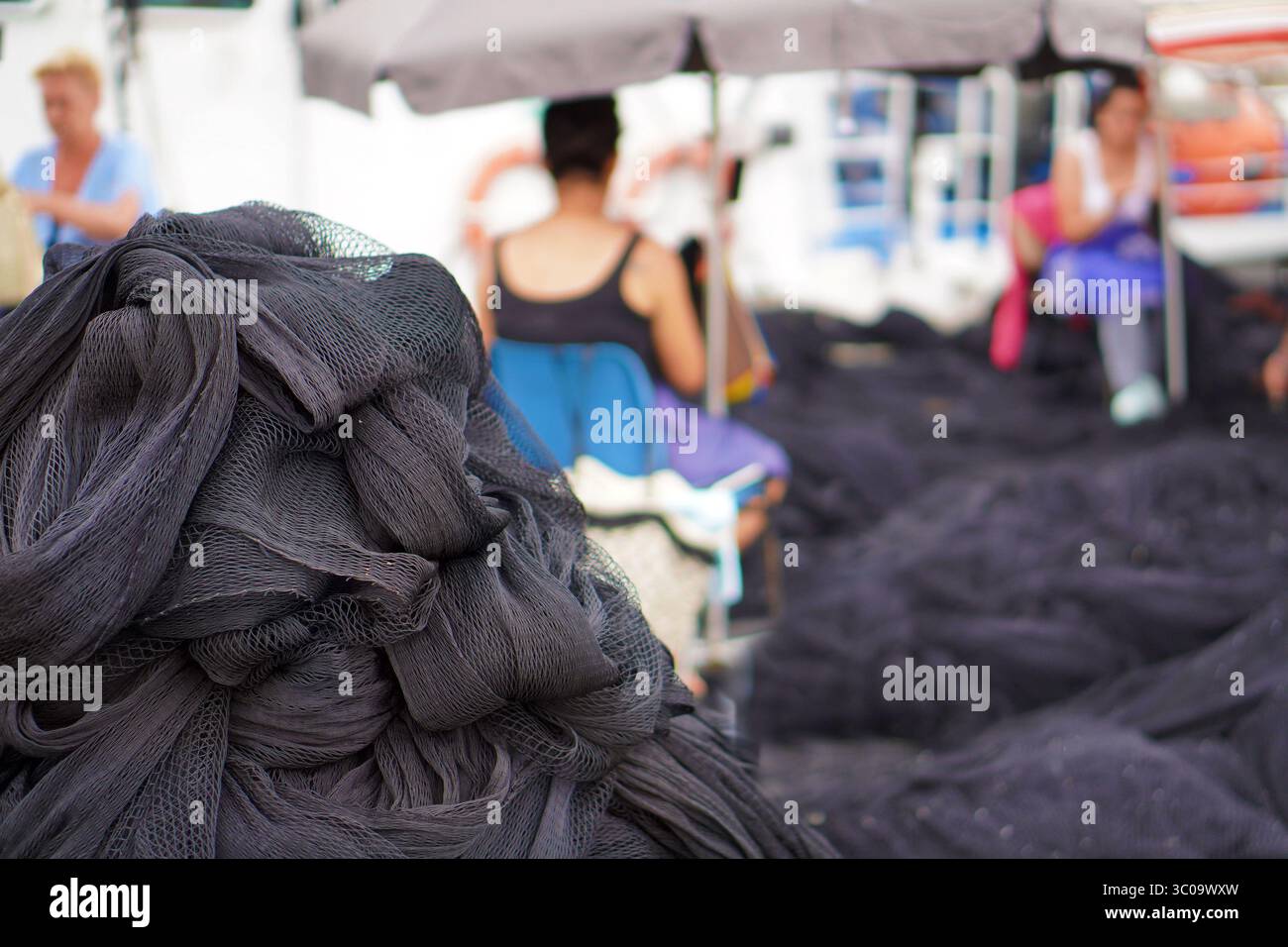 fishing industry. traditional trades. pile of nets stacked with women ...