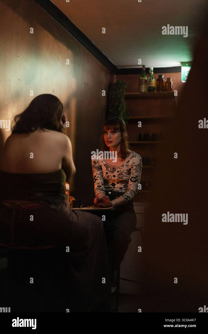 Intimate conversation between two women in a dimly lit bar corner Stock ...