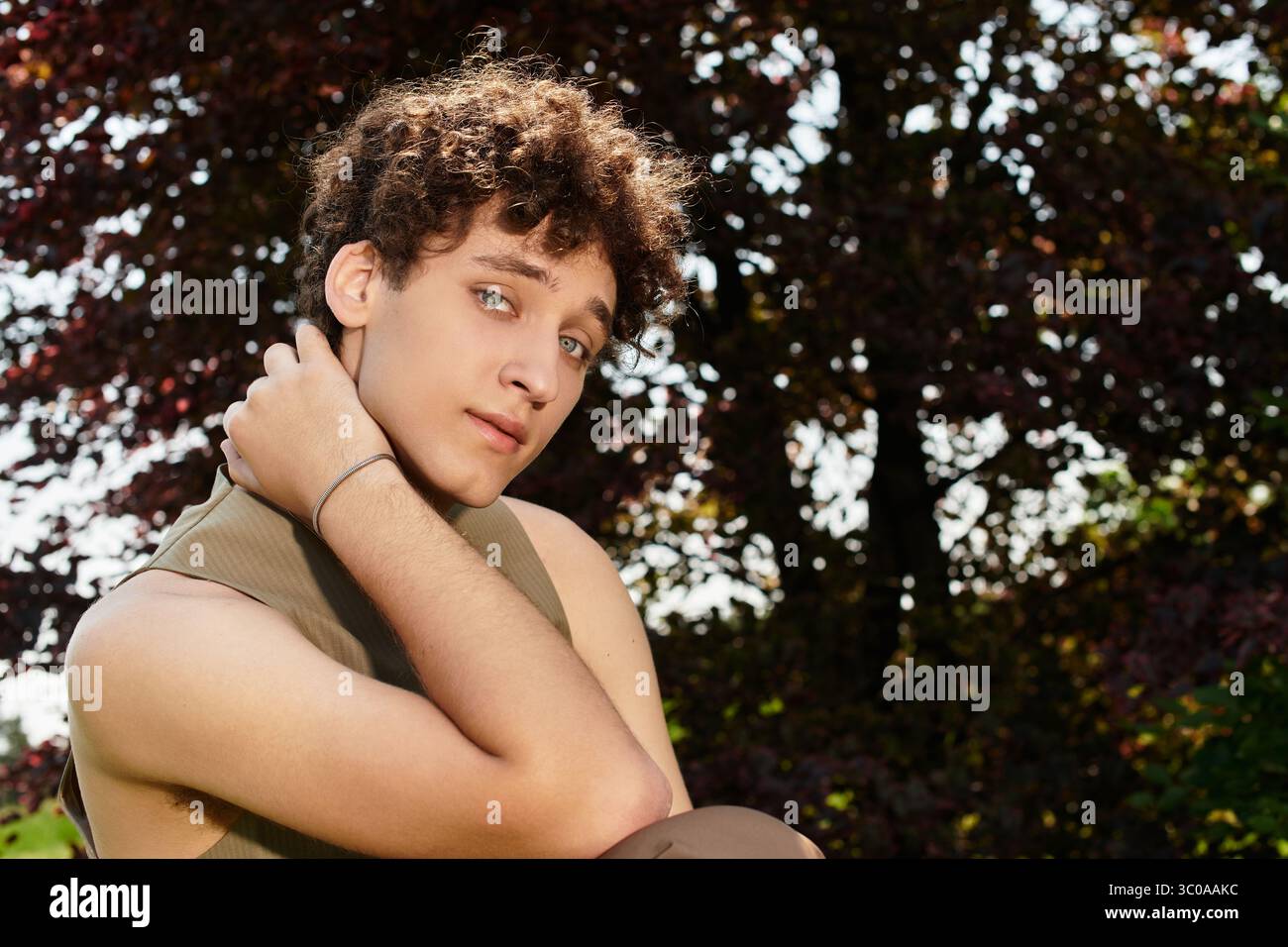 A stylish young man enjoys a sunny day in a vibrant park, showcasing ...