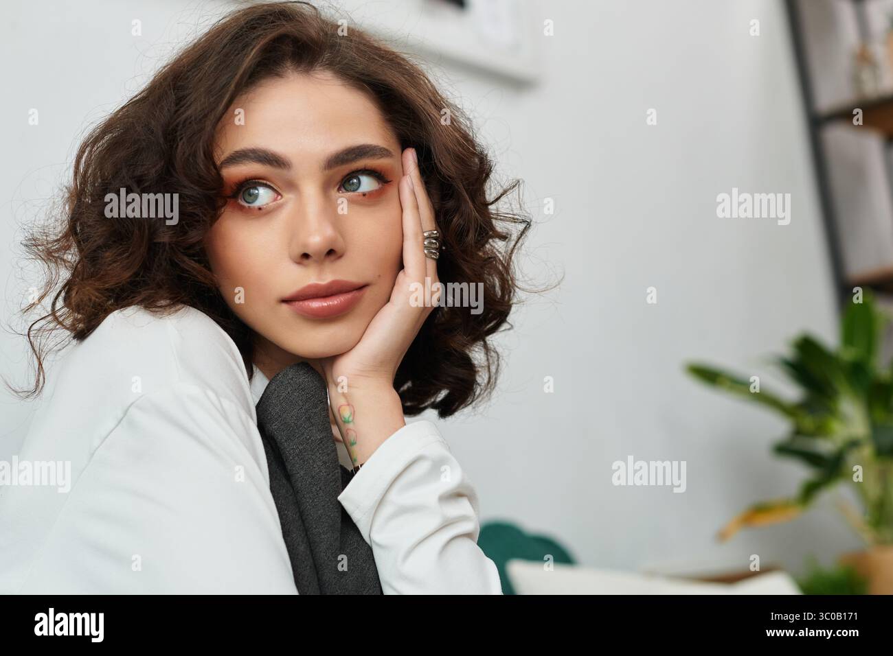 A young woman with curly brown hair relaxes in her chic apartment ...