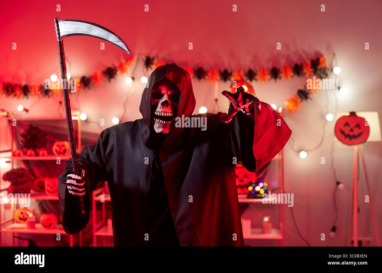 Halloween decorated room, scary person in black Grim Reaper costume ...