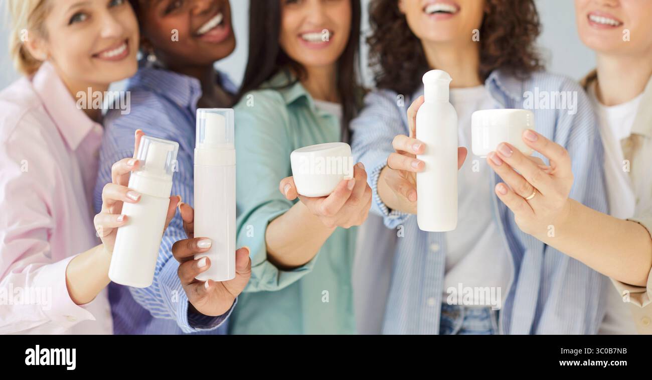 Group of smiling cheerful women holding containers with cream ...