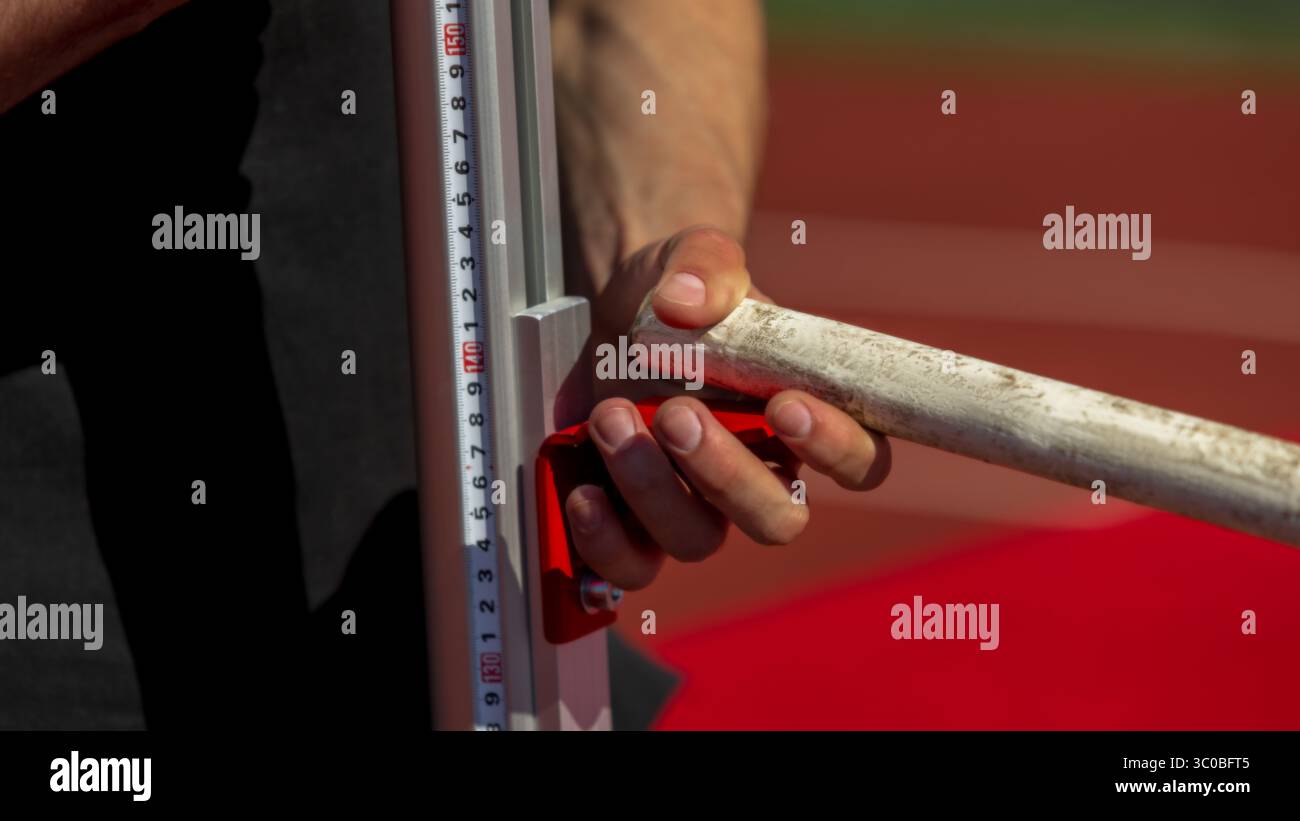 Closeup of athlete's hand holding pole next to height gauge on a track ...