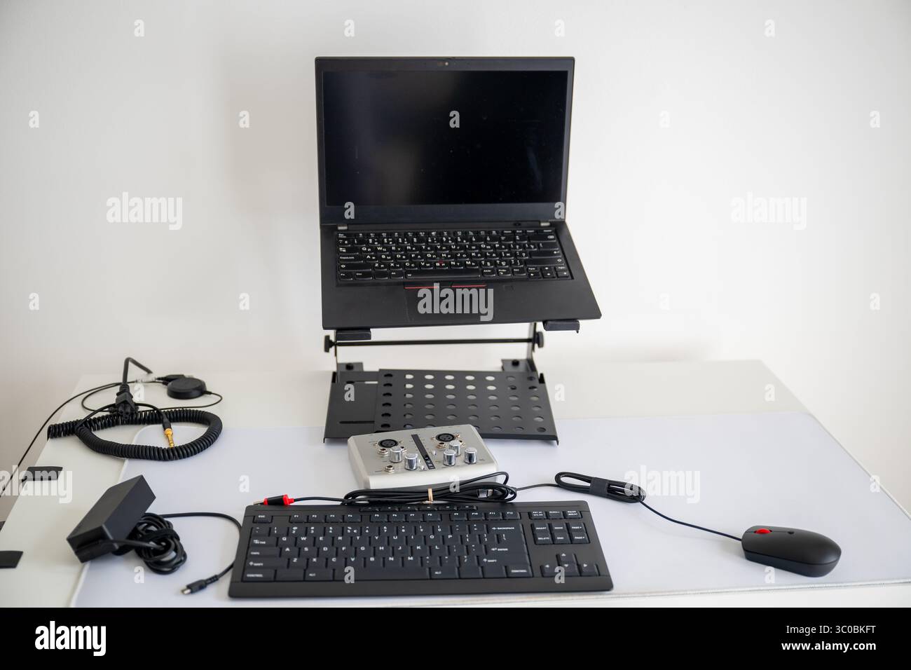 Minimalist home office setup with laptop on stand, keyboard, mouse, and ...