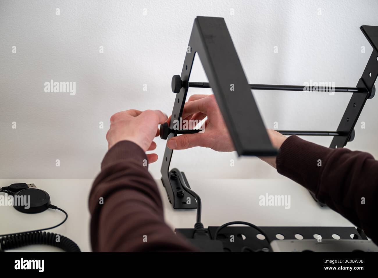 person adjusting ergonomic metal laptop stand on white desk in home ...