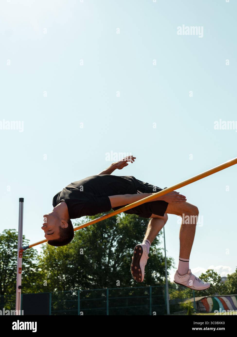 Athlete airborne while performing high jump on sunny day at open-air ...
