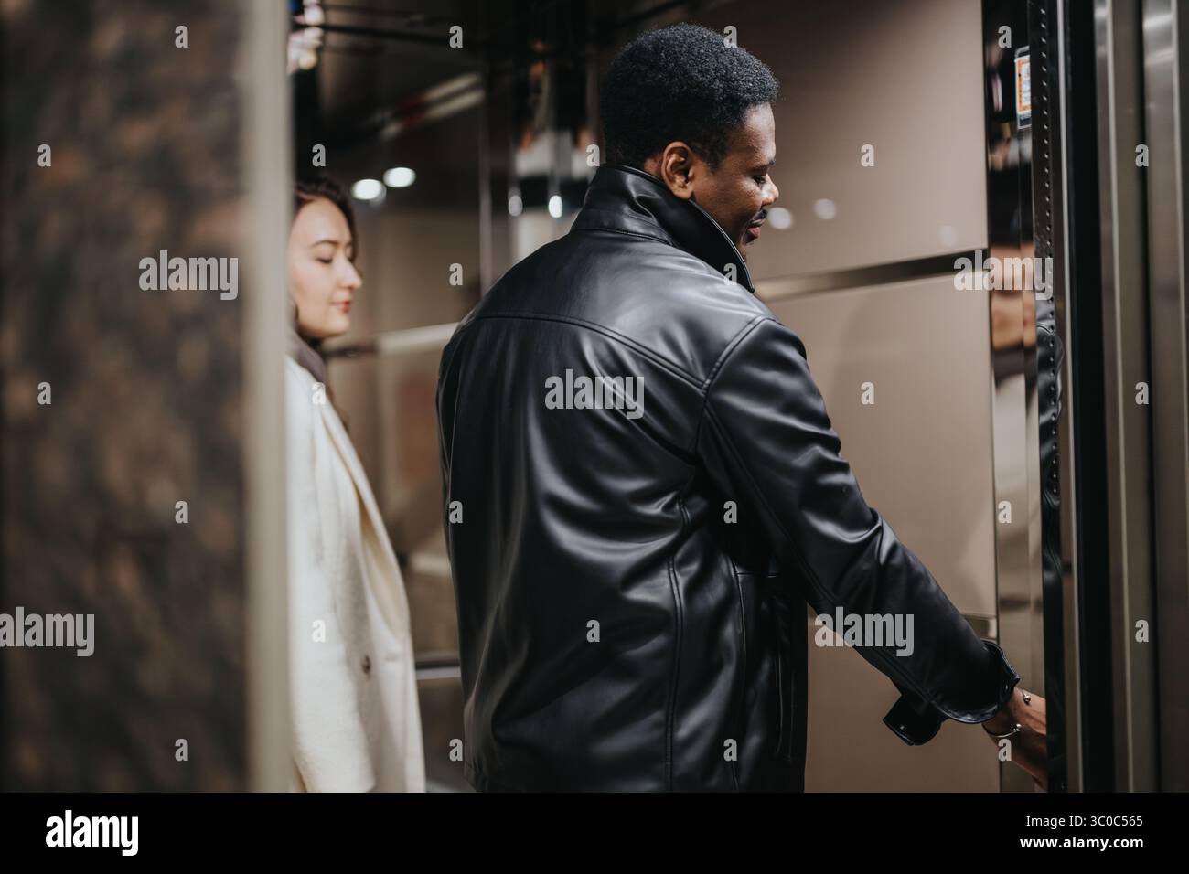 Two people using an elevator with a sleek interior, one pressing a ...