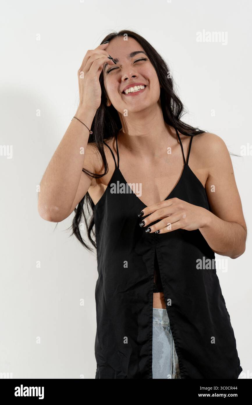 Cheerful young woman with long dark hair, wearing a black top, smiles ...