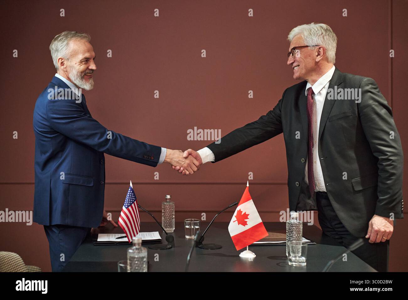 Middle aged Caucasian men shaking hands across table during diplomatic ...
