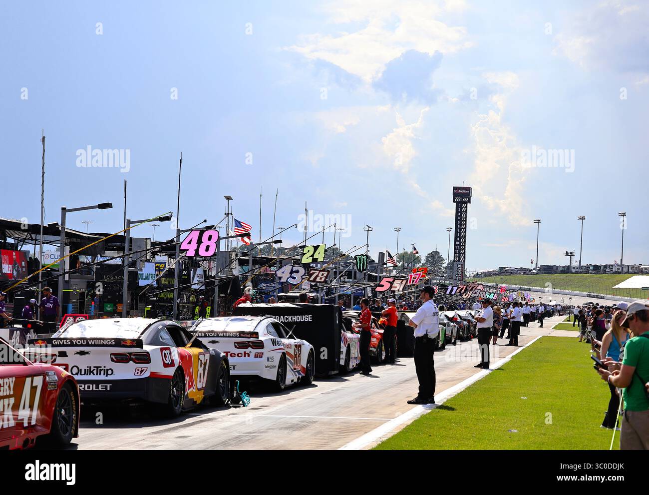 Cars sit on pit road ahead fo the 2025 Quaker State 400 as storm clouds ...