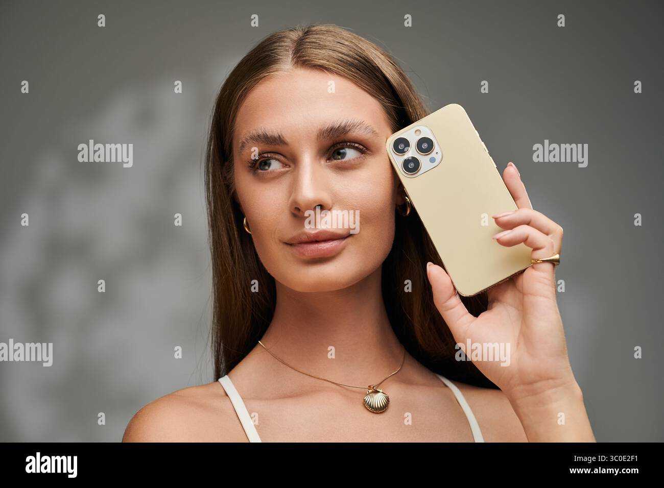 A beautiful young woman with tan skin is posing with smartphone in a ...