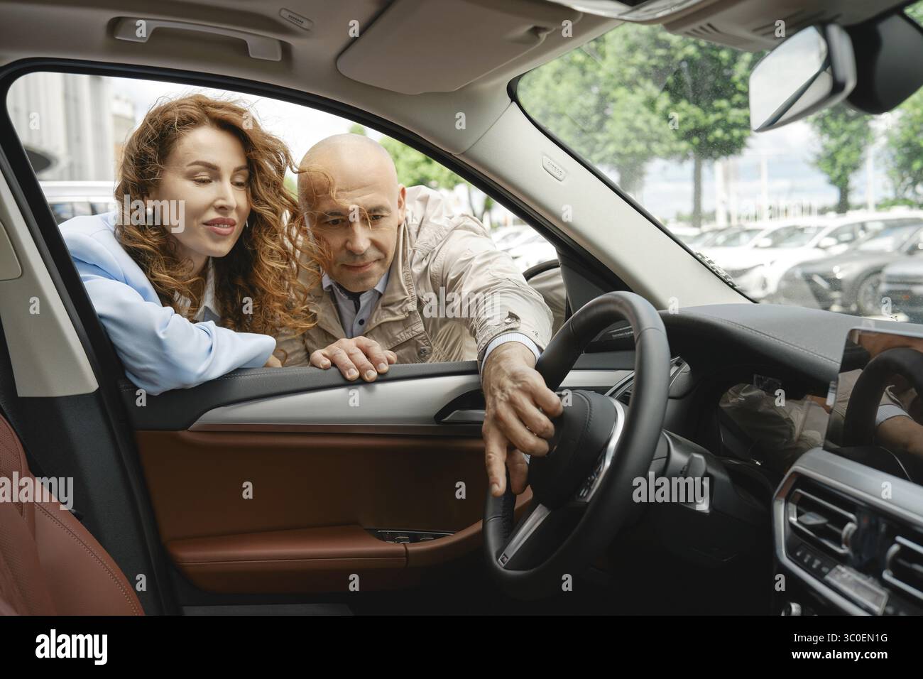 A couple examines the interior of a vehicle looking through the open ...