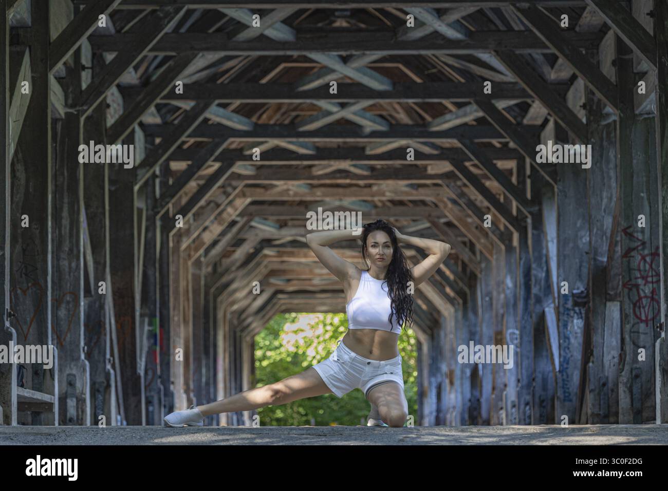 Woman in white sports outfit posing on the floor of a bridge with ...