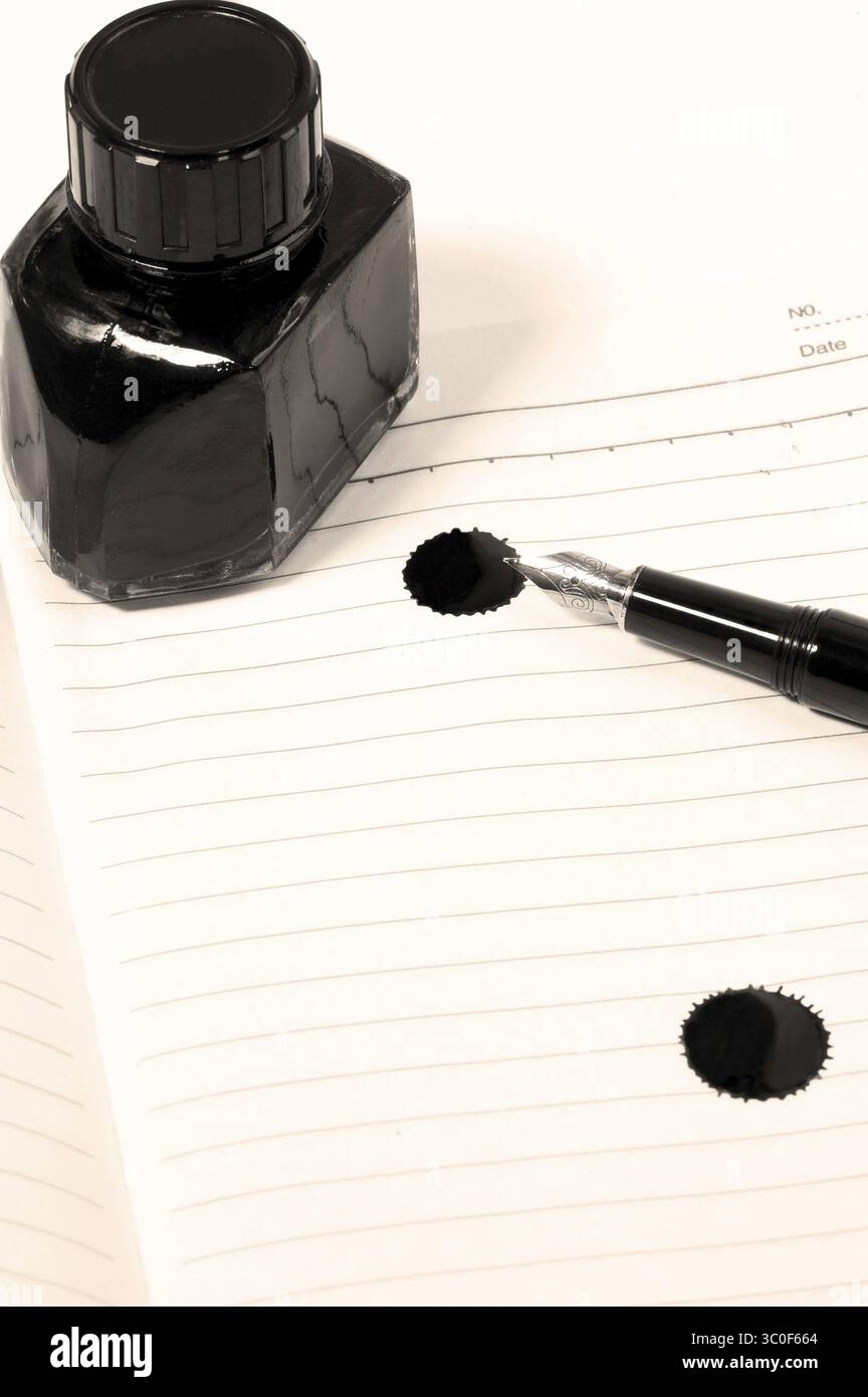 Classic black fountain pen on open notebook with ink bottle with stain ...