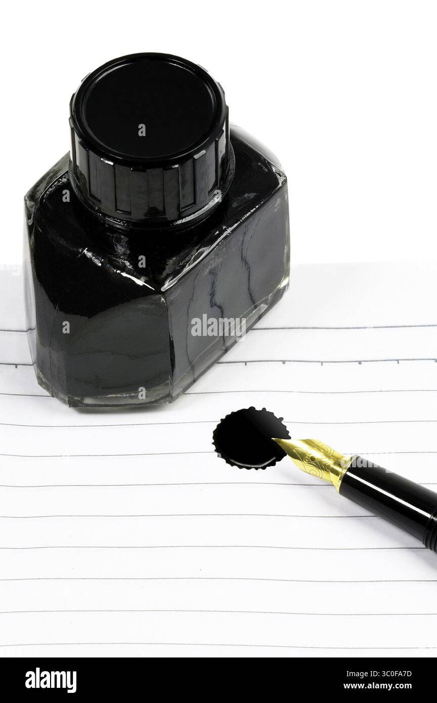 Classic black fountain pen on open notebook with ink bottle with stain ...