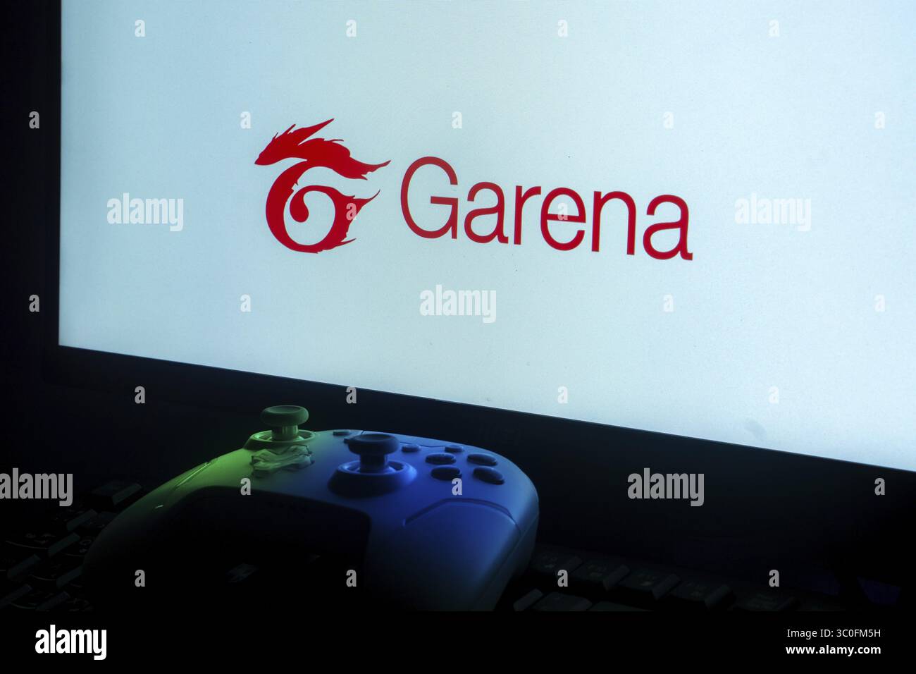 Garena logo on a screen with a gaming controller silhouette Stock Photo ...