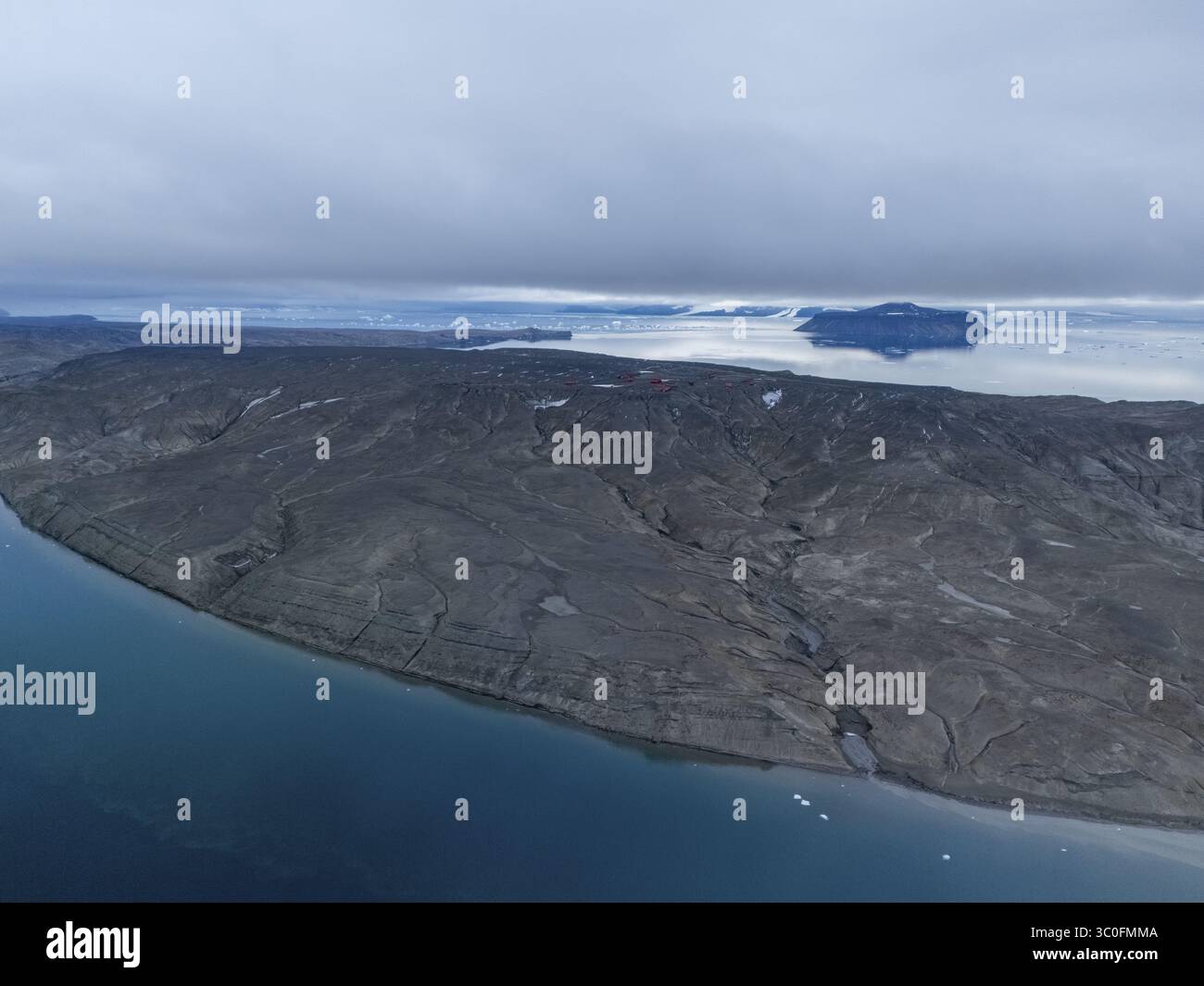 Aerial view of a dark, rugged landscape meeting the serene, icy sea ...