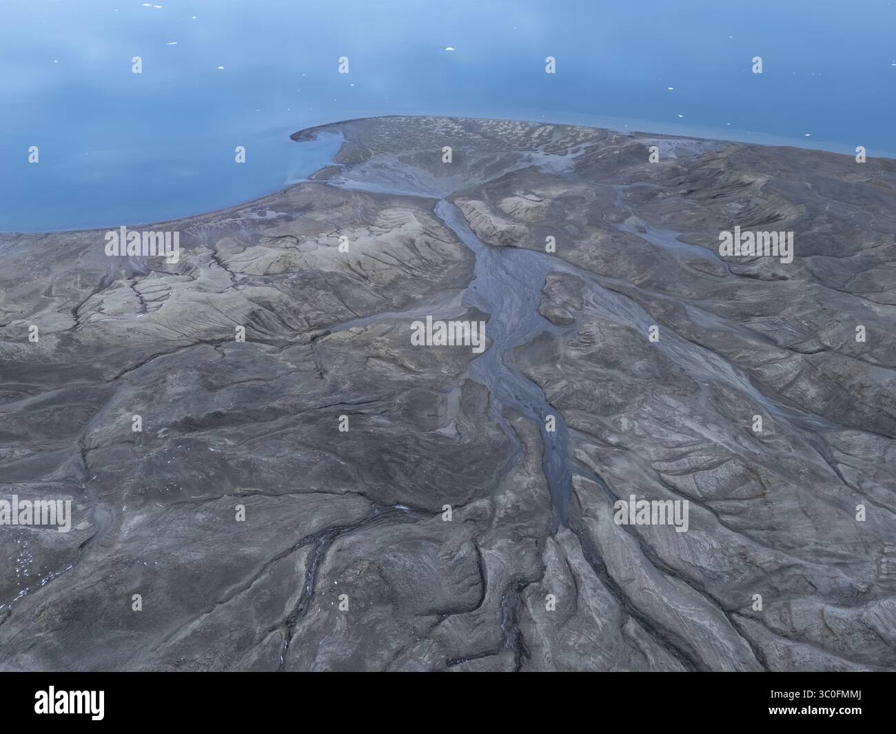 Aerial view of the stark, grey, cracked earth meeting the cool, blue ...