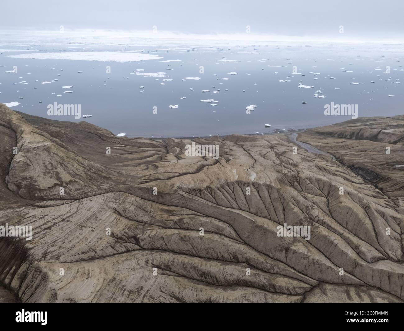 Aerial view of the stark, textured terrain meeting the icy sea dotted ...