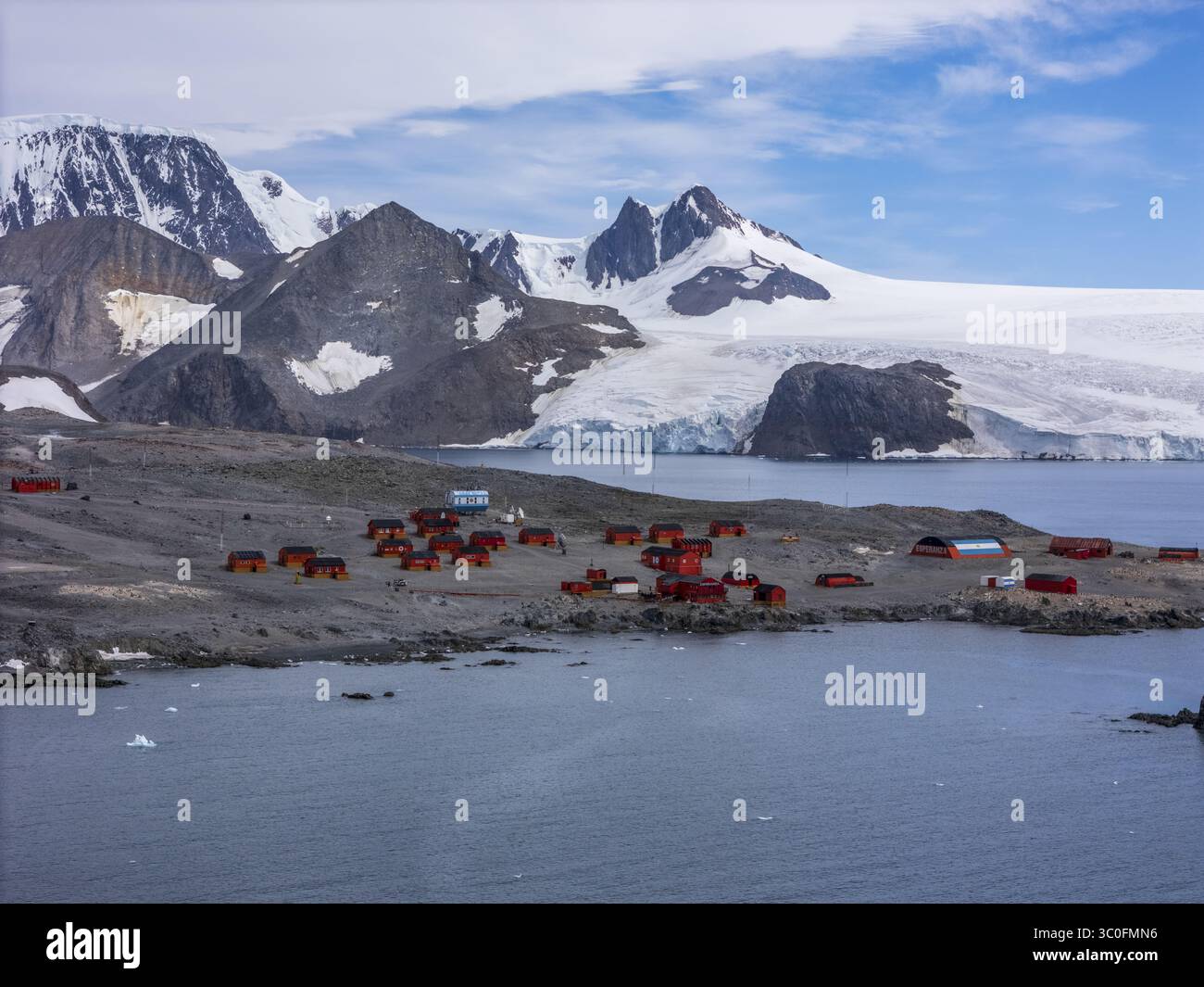 Aerial view of red-roofed buildings nestled on a rocky shore with snow ...